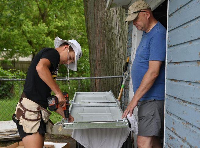 Nathan Porterfield, 15, left, and Chuck Dieter assemble a new garage ...